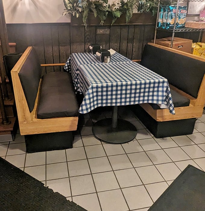 The booth seating offers a front-row view to the cheesesteak show—where blue checkered tablecloths have witnessed countless first bites and satisfied sighs.