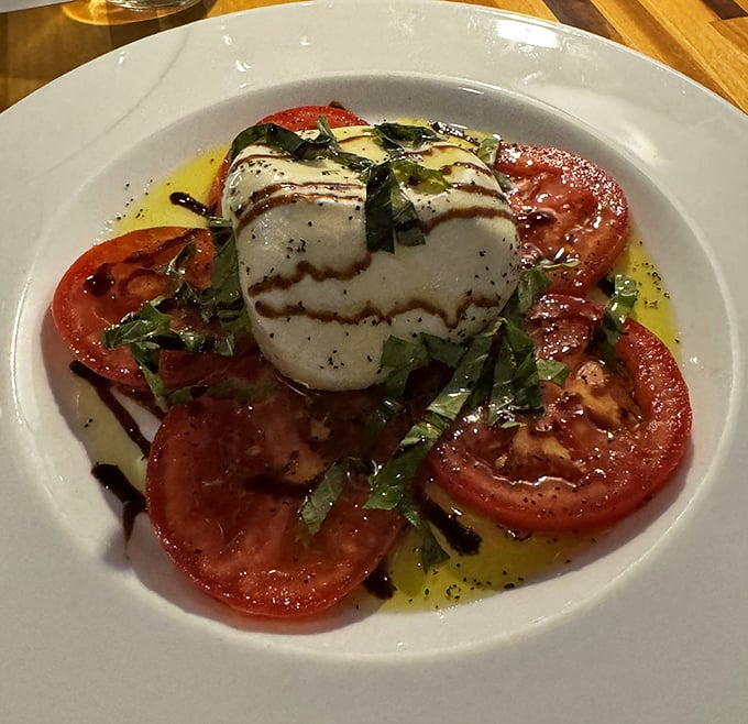 A proper Caprese salad that proves sometimes the simplest combinations—ripe tomatoes, fresh mozzarella, basil, and good olive oil—are culinary perfection.