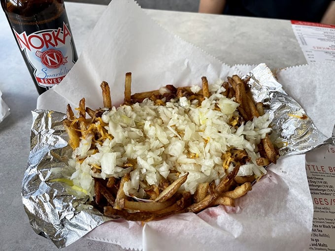 Fries elevated to main course status with a blanket of chili and a snowfall of diced onions—fork required, no sharing allowed.