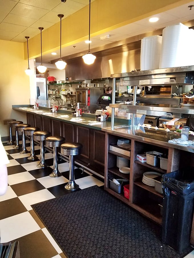 The diner counter—where solo diners become regulars and the magic happens behind stainless steel. A front-row seat to breakfast theater.
