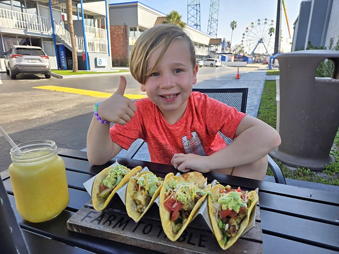 The universal sign of food happiness: a thumbs-up from a kid with tacos. No focus groups needed—this is the real seal of approval.