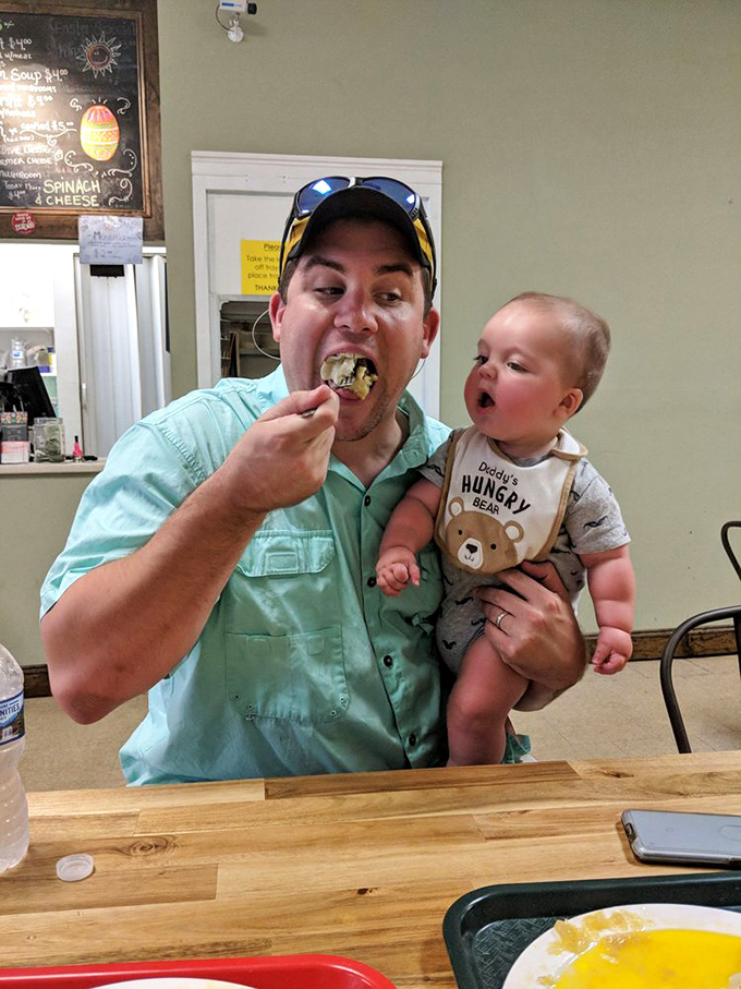 The image shows a customer enjoying a pierogi while holding a baby—proving that good taste is hereditary and Polish comfort food spans generations.