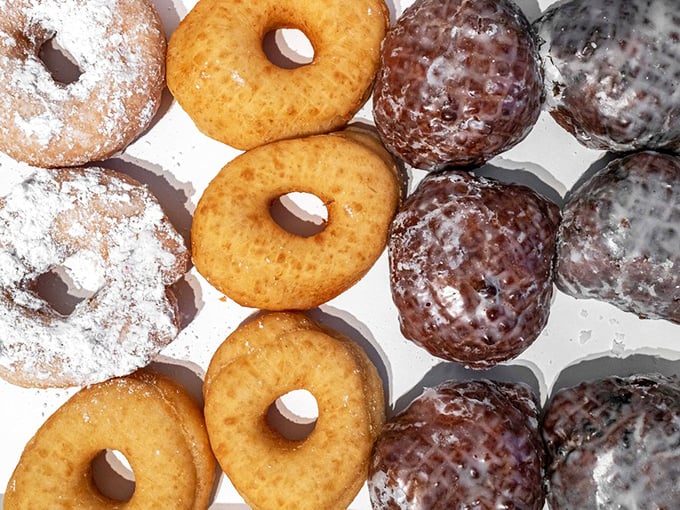 A box of possibilities—where powdered, glazed, and chocolate-dipped neighbors coexist in perfect harmony, waiting for your impossible decision.