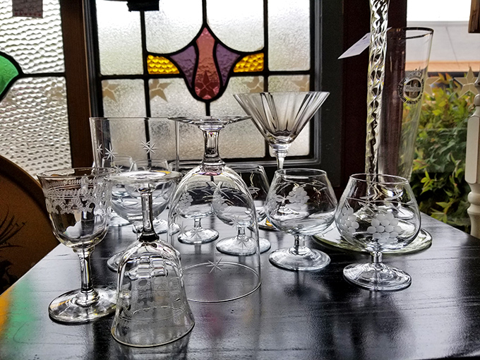 Etched glassware catching light against stained glass—these aren't just drinking vessels, they're tiny crystal museums of mid-century entertaining elegance.