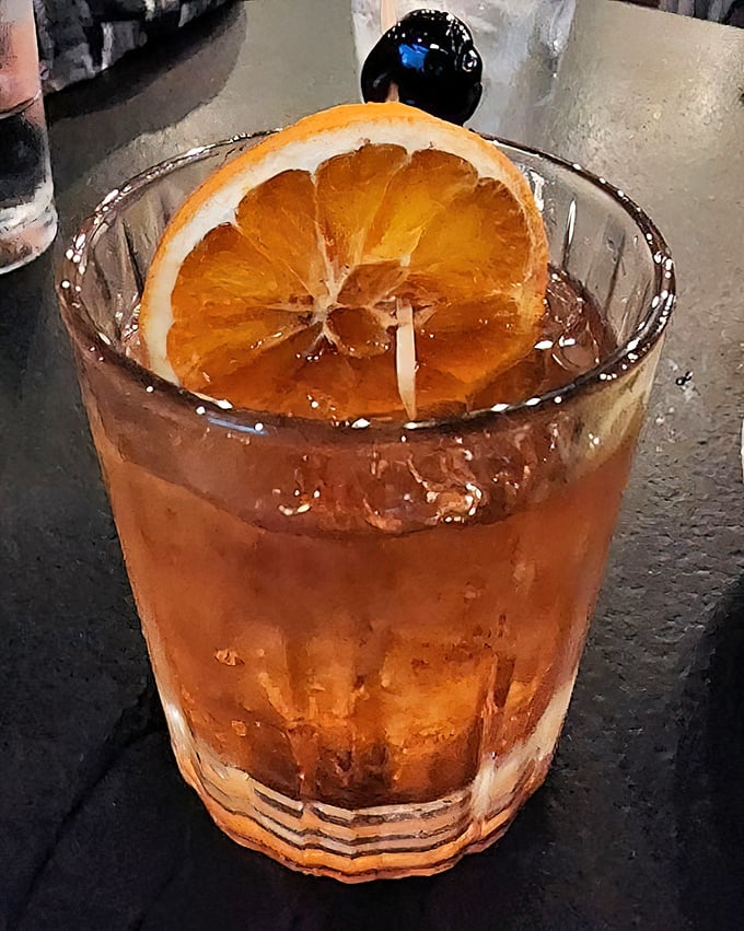 An Old Fashioned with a proper orange slice—cocktail simplicity at its finest. Amber liquid catching light like liquid nostalgia.