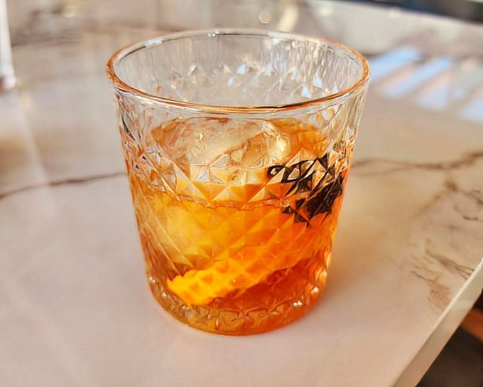 This isn't just an Old Fashioned—it's a sunset captured in crystal, with that orange peel twist adding a splash of citrus drama.