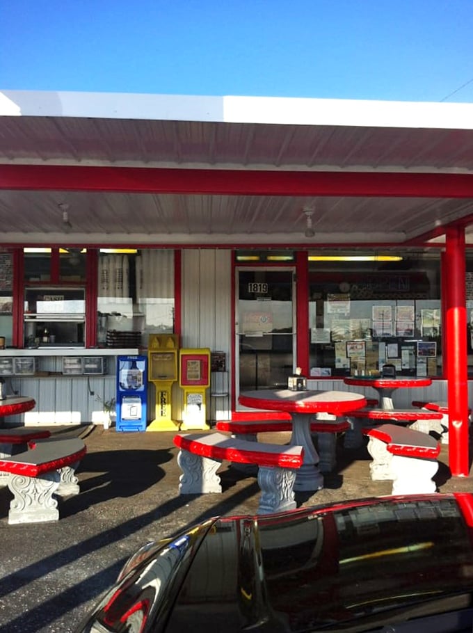 The outdoor seating area—where Florida sunshine meets American classics. These red tables have supported more happy elbows than an orthopedic clinic.