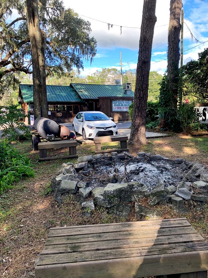 Where smoke meets sky – the fire pit and outdoor seating area promise an authentic barbecue experience under Spanish moss-draped trees.