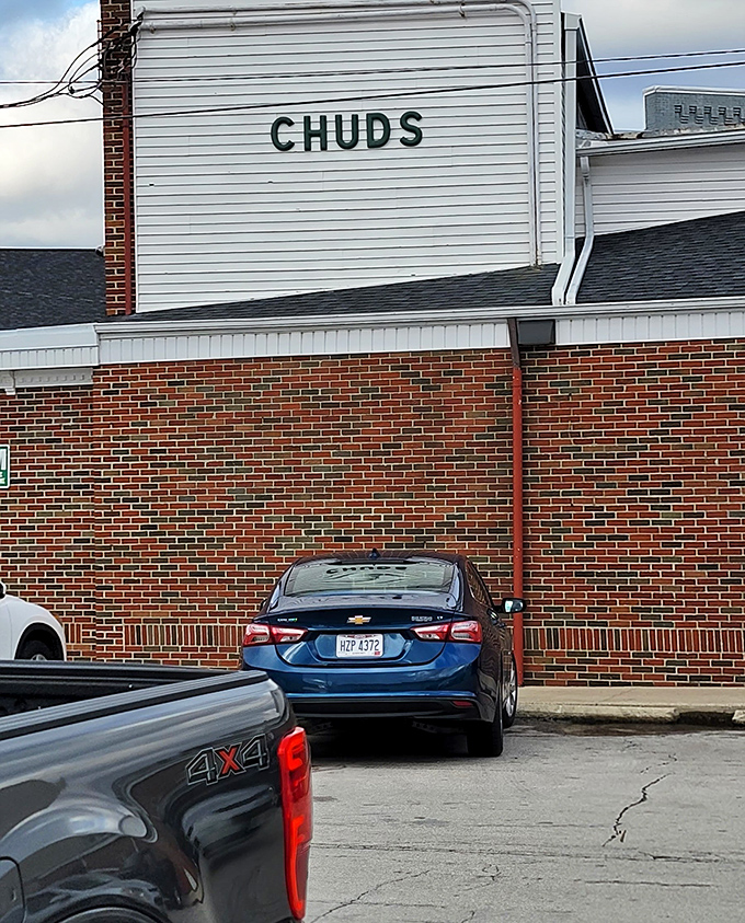 The unassuming parking area outside Chud's—where hungry arrivals and satisfied departures create a constant cycle of culinary happiness.