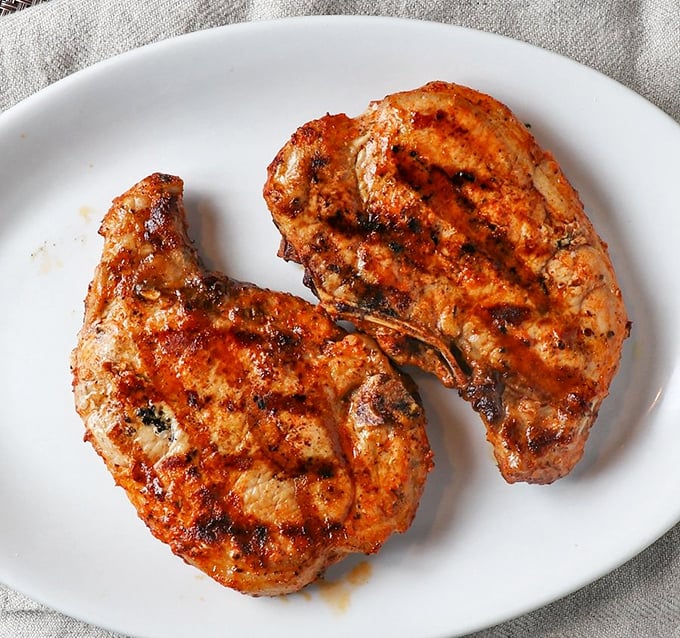 Two perfectly grilled pork chops on a pristine white plate—minimalist food art that speaks volumes without saying a word.