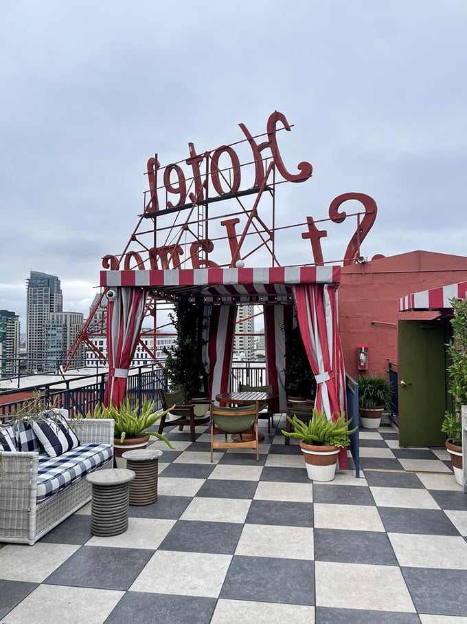 "Hotel" spelled backward on the rooftop creates an Alice-in-Wonderland charm. Red and white striped awning against the San Diego skyline—whimsy with a view.
