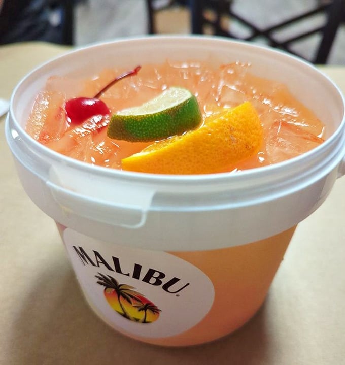 This rum bucket isn't just a drink—it's a vacation in a container, where fruit garnishes float like colorful buoys in a sea of tropical refreshment.