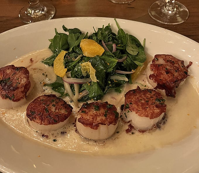 These scallops aren't just perfectly seared—they're surrounded by spinach like royalty holding court in a pool of cream sauce fit for culinary nobility.