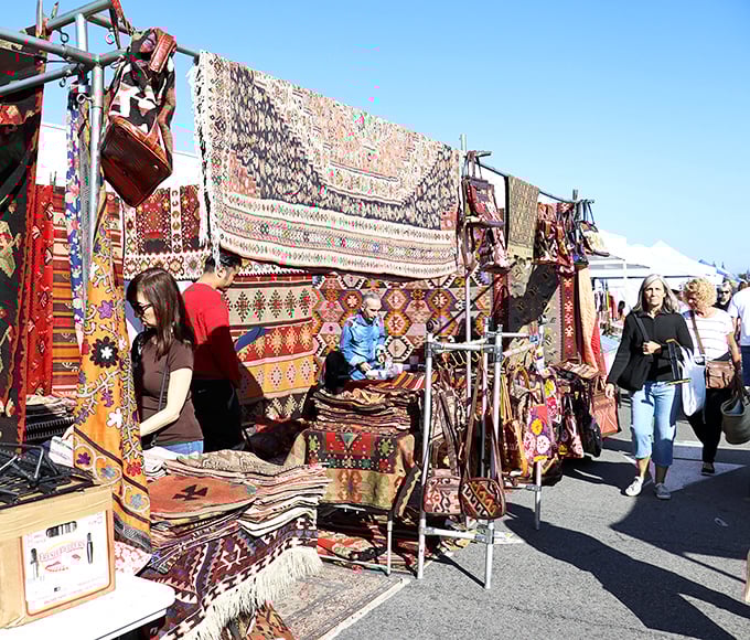 Textile heaven unfolds as shoppers browse handwoven rugs from distant lands—each one telling stories of ancient patterns and traditions through vibrant threads and intricate designs.