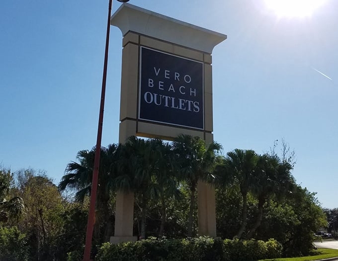 The Vero Beach Outlets sign stands tall, a beacon of hope for bargain hunters and fashion enthusiasts alike.