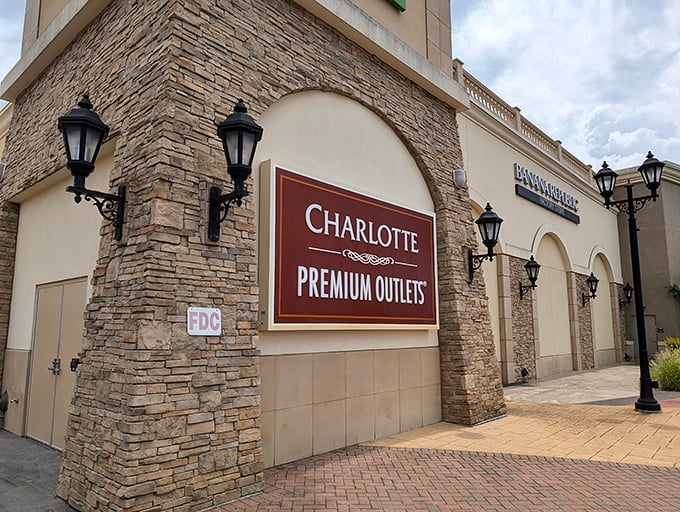 The stone facade and elegant signage suggest upscale shopping, while your wallet whispers grateful thanks for outlet pricing.