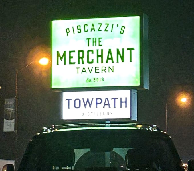 The sign glows like a beacon for hungry travelers. "Piscazzi's The Merchant Tavern" promises refuge from ordinary dining experiences since 2013.