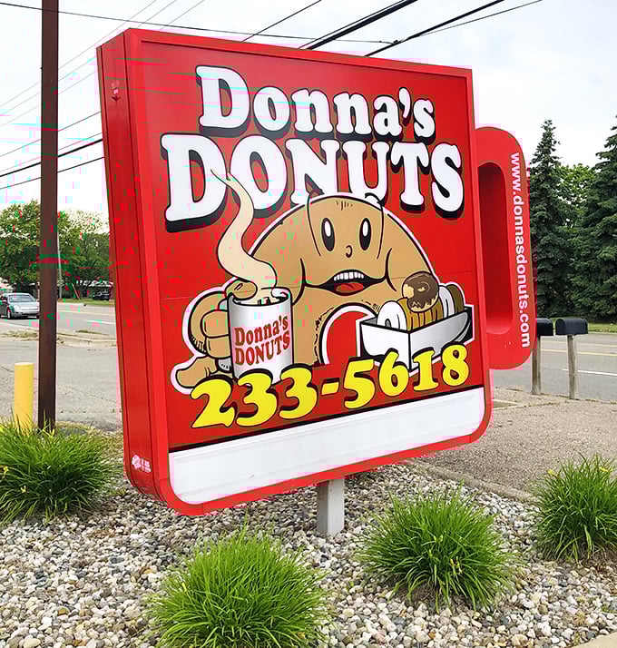 The cheerful roadside sign features their donut mascot—looking suspiciously happy for someone whose friends keep disappearing into boxes.