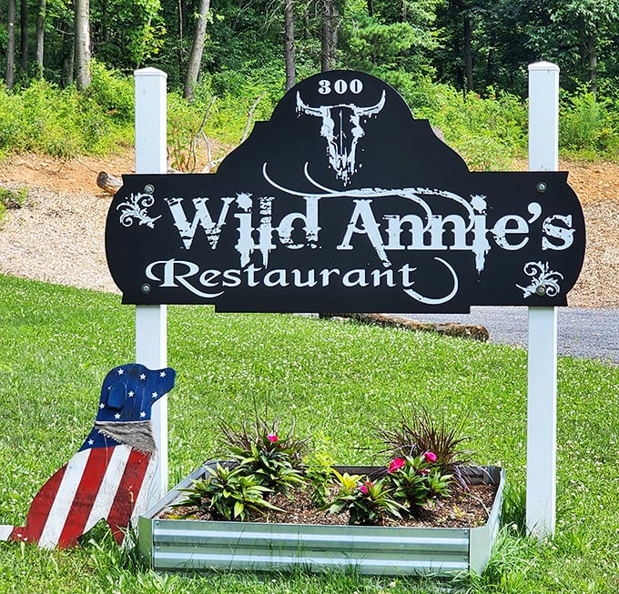 The entrance sign stands as a rustic welcome beacon, promising good times and great food just beyond those white posts.