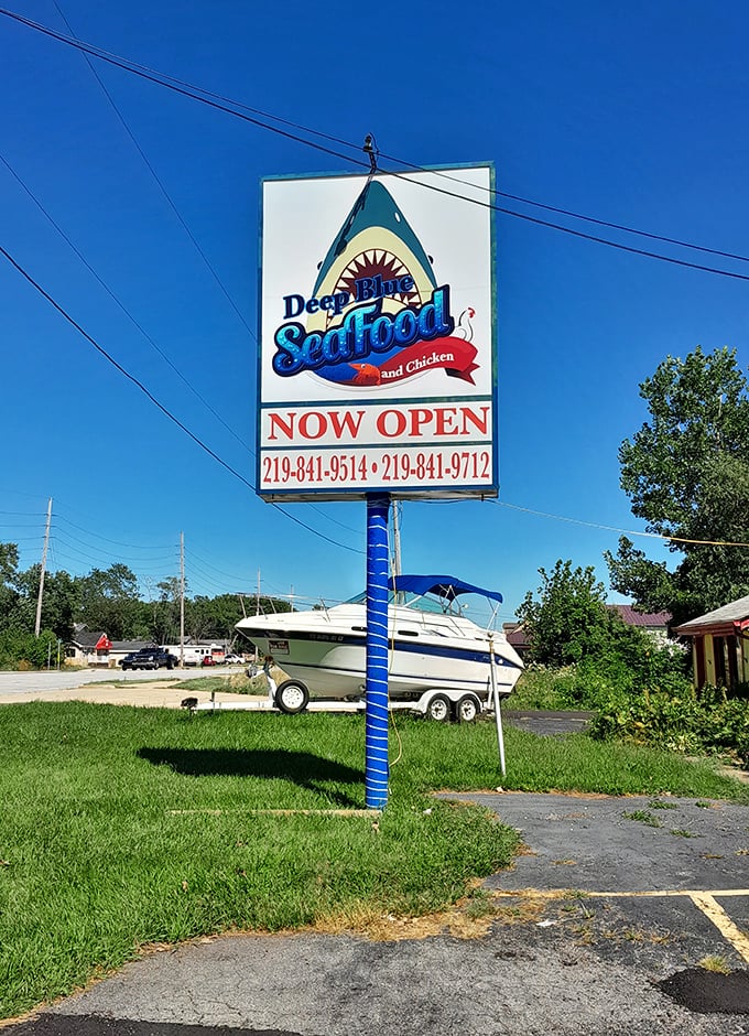 The roadside sign stands tall, a blue beacon for seafood lovers. And yes, that's a boat in the background—a fitting neighbor.