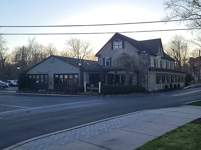 As dusk settles over Yardley, the inn's silhouette against the evening sky promises warmth and satisfaction within its historic walls.