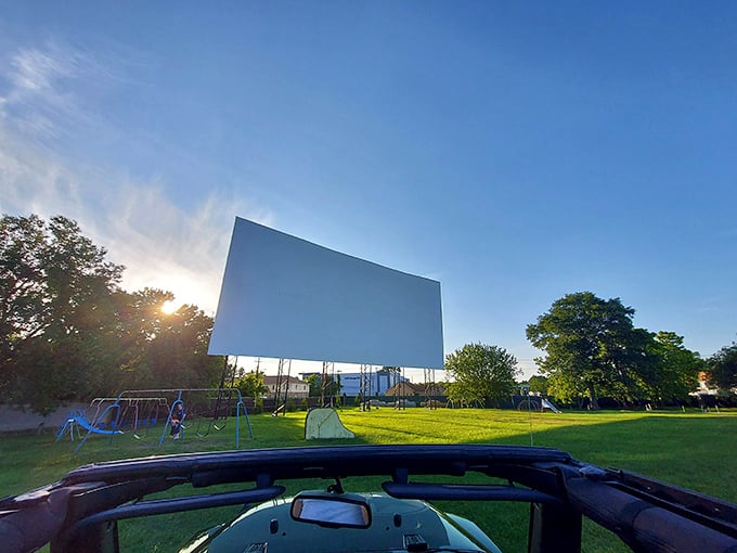 Dawn breaks behind cinema's cathedral. The massive screen stands sentinel over morning dew, waiting for darkness to bring it back to life.