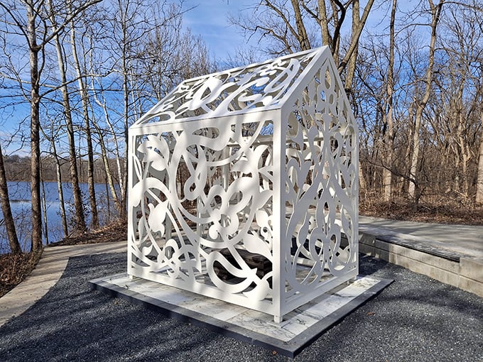 This Is Not a Refuge stands like a delicate paper house by the water, its intricate cutouts creating ever-changing patterns of light and shadow.