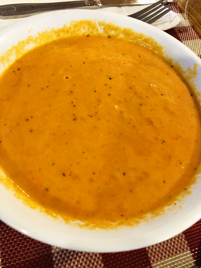 A bowl of sunshine disguised as tomato basil soup—the kind that makes you want to hug the chef and request the recipe.