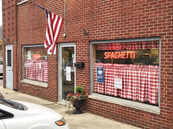 The American flag waves proudly outside this pizza institution. Red-checkered curtains promise old-school Italian goodness waiting inside.