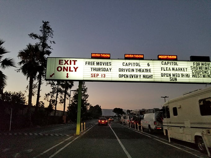 The iconic entrance sign glows against the dusk, promising "FREE MOVIES THURSDAY" and announcing the weekend flea market—a beacon of entertainment options.