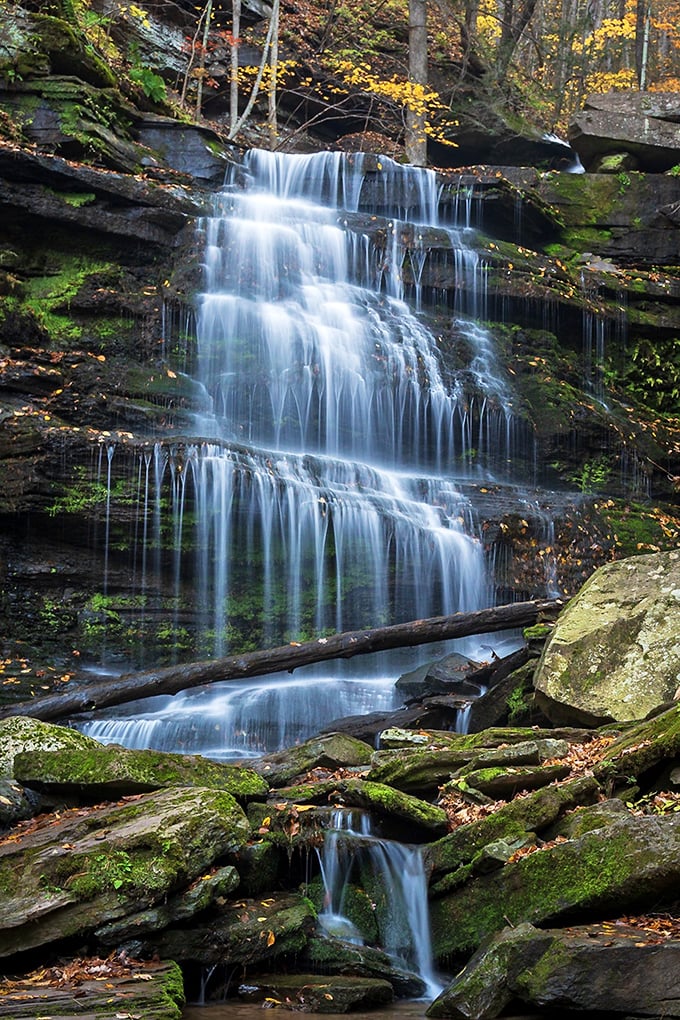 Water doesn't just fall here—it performs, cascading over ancient rock formations like nature's own symphony orchestra playing a timeless melody.