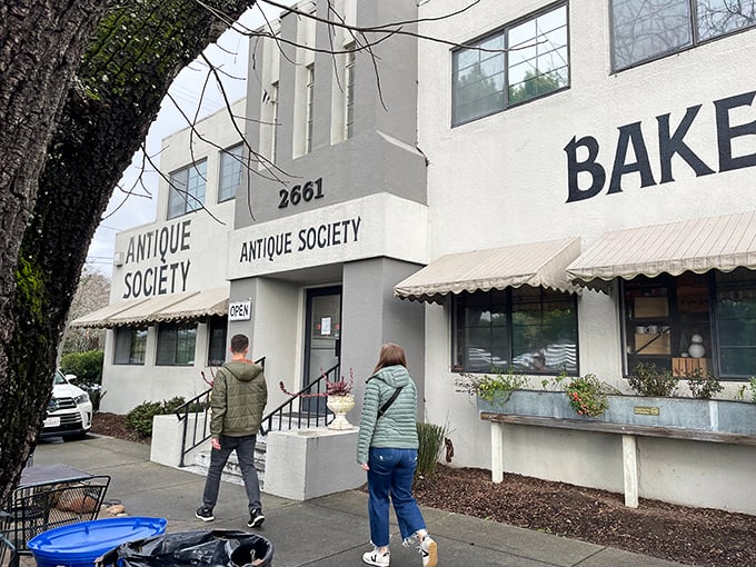 Two treasure hunters approach the entrance, where "BAKERY" promises sustenance for those whose antiquing stamina might need a boost.