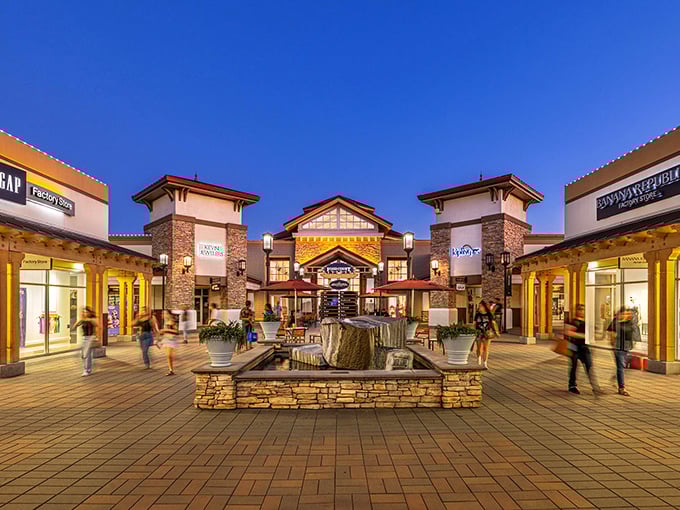 As dusk settles, the central plaza transforms into a glowing retail oasis. That fountain isn't for wishes—it's for resting your shopping bags while plotting your next store conquest.