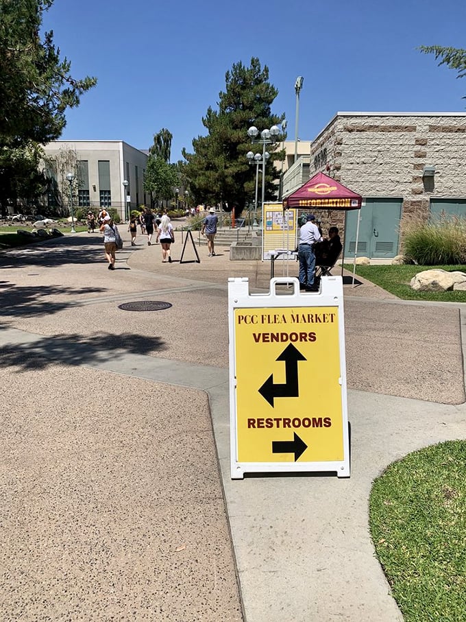 The yellow directional sign says it all—vendors this way, restrooms that way. The universal language of flea market navigation never fails.