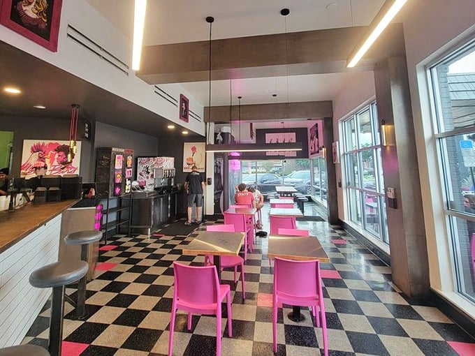 Step inside and the retro-modern vibe hits you immediately – black and white checkerboard floors meet hot pink chairs in a space that screams "Instagram me, but eat the chicken first!"