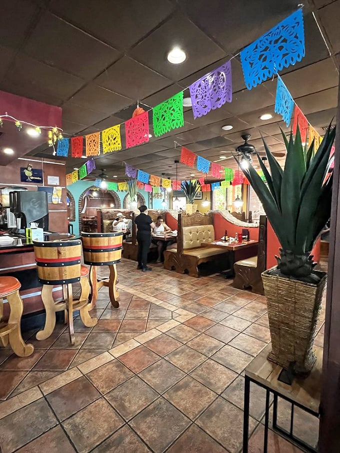Colorful papel picado banners dance overhead while barrel-style chairs await hungry patrons. This isn't decoration—it's a portal to Mexico.