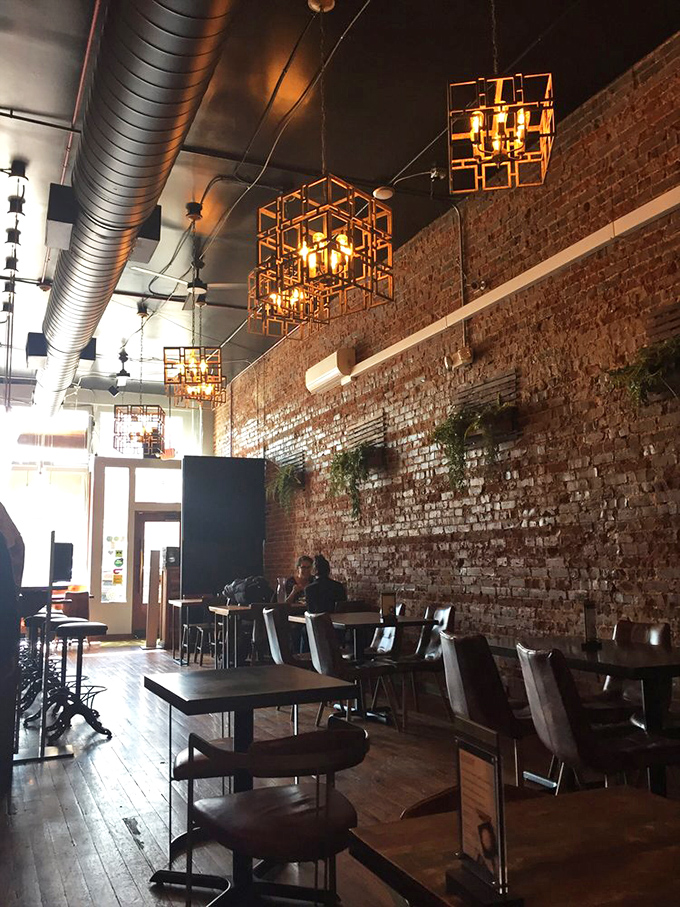 Exposed brick walls meet geometric lighting in this stylish interior where industrial chic creates the perfect backdrop for culinary adventures.