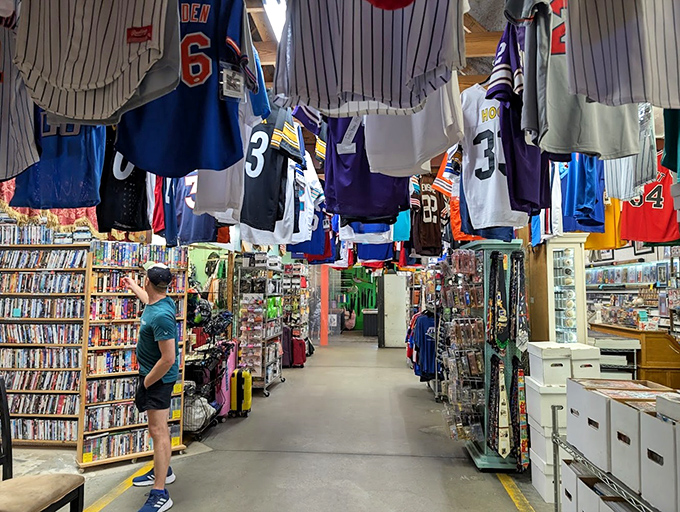 Sports jerseys hang like championship banners above aisles of DVDs. A shopper contemplates which forgotten classic deserves resurrection in his home theater.