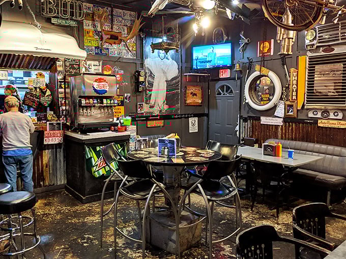 Step inside and time warps beautifully – license plates, vintage signs, and industrial charm create the perfect backdrop for serious burger business.