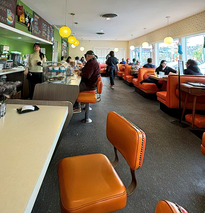 Those vibrant orange booths aren't just seating—they're time machines to an era when conversation trumped Instagram and comfort outranked trendiness.