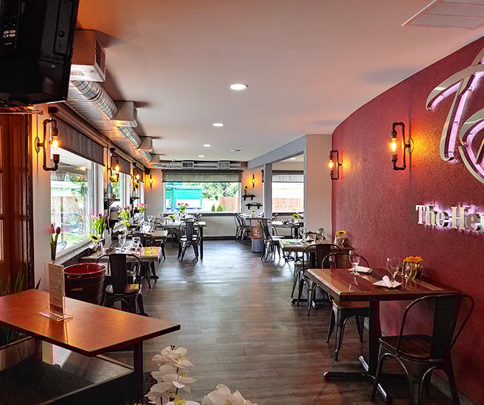 The warm burgundy accent wall and industrial-chic seating create that perfect sweet spot between "nice enough for date night" and "comfortable enough for breakfast in sweatpants."