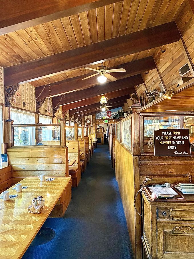 Wooden booths line the walls inside this cozy Alpine-inspired interior, where breakfast dreams come true under warm pine paneling and exposed beams.