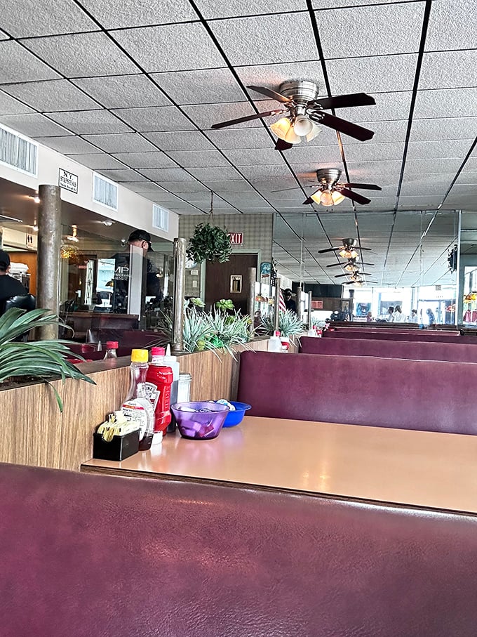 Inside, burgundy vinyl booths and wood paneling create a time capsule where conversations flow as freely as the coffee refills.
