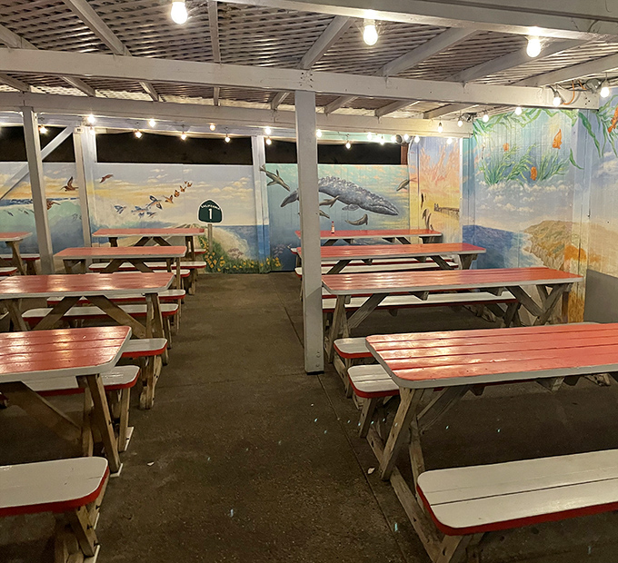 The covered patio with ocean-themed murals offers a casual, breezy dining experience. Picnic tables beat white tablecloths any day here.