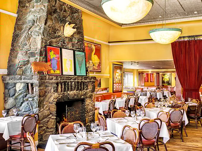 Yellow walls, vintage posters, and that magnificent stone fireplace – this dining room doesn't just serve French cuisine, it wraps you in a Parisian embrace.