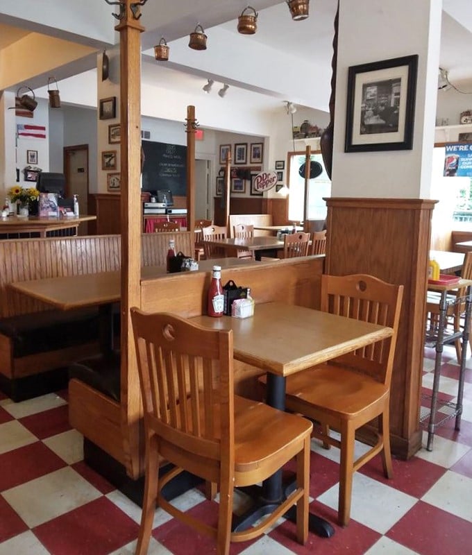 Wooden booths worn smooth by decades of satisfied customers create little islands of privacy where conversations flow as freely as the coffee.