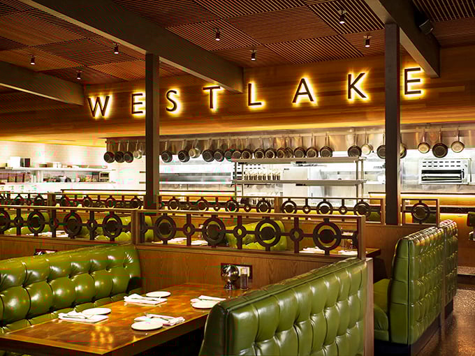 Those green leather booths aren't just seating—they're front-row tickets to culinary theater, with the exhibition kitchen's hanging pots promising delicious performances.