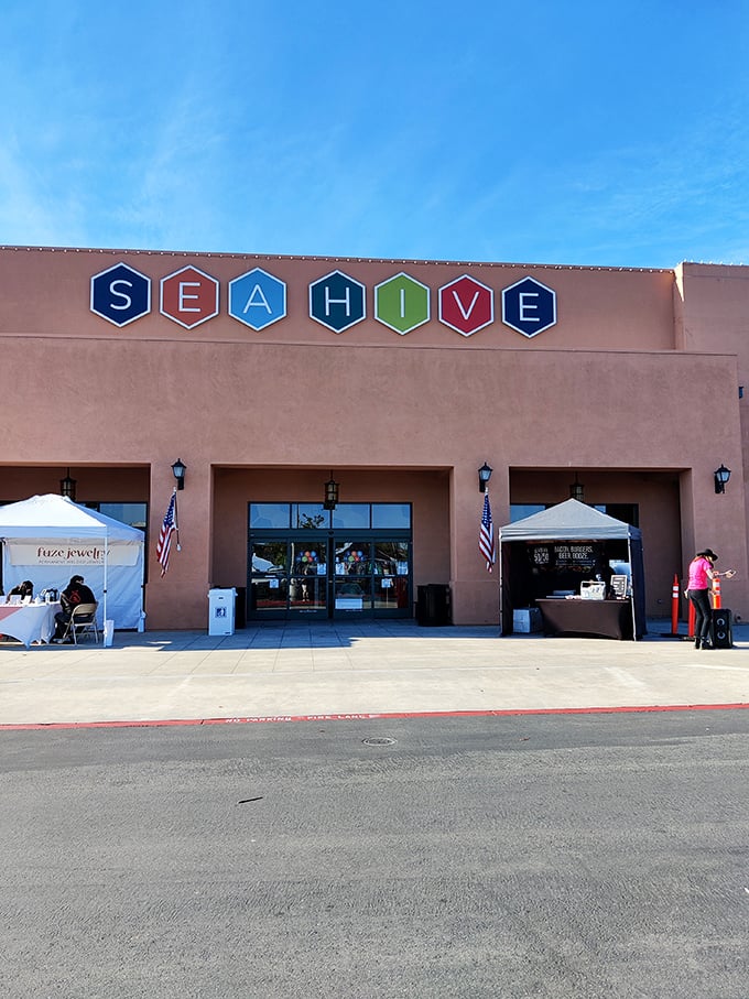 A second view of Sea Hive's inviting façade, where American flags flutter beside pop-up vendor tents, hinting at the community of creators inside.
