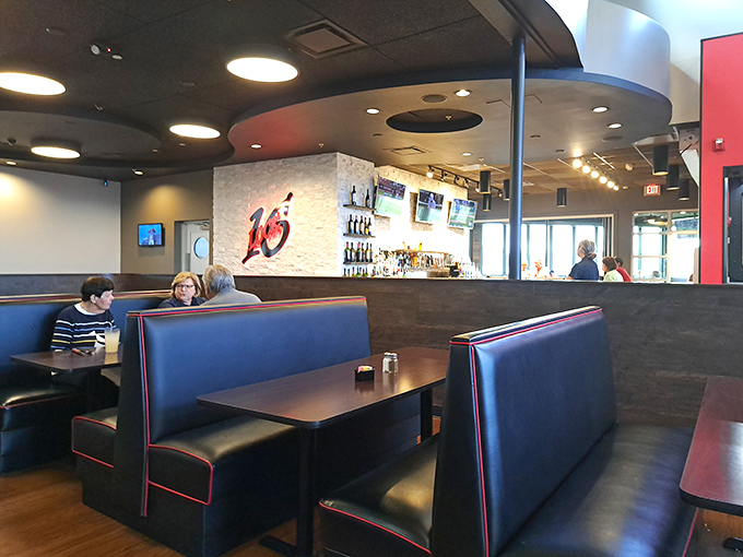 Sleek navy booths with striking red trim offer comfortable seating in an atmosphere that balances upscale dining with unpretentious comfort.