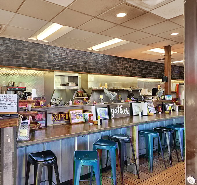 Counter seating puts you front-row for the breakfast show. Blue metal stools, brick walls, and that "gather" sign—they had me at hello.